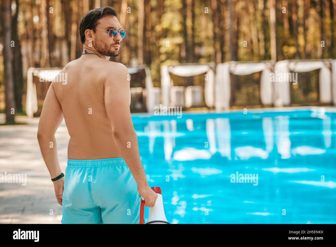A lifeguard in blue shorts standing near the swimming pool Stock Photo ...