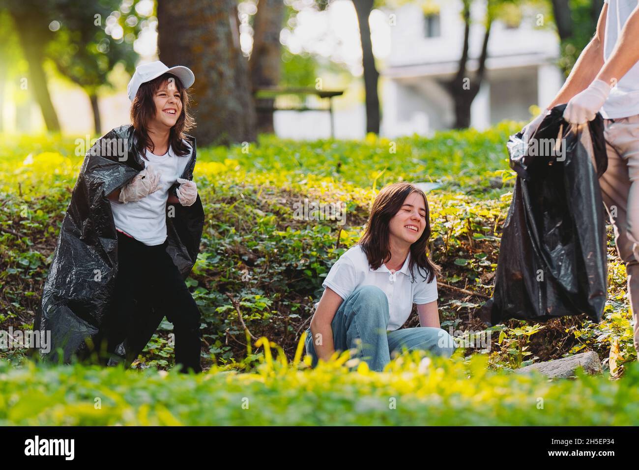 Three people participate in gathering the rubbish outdoors in gloves ...