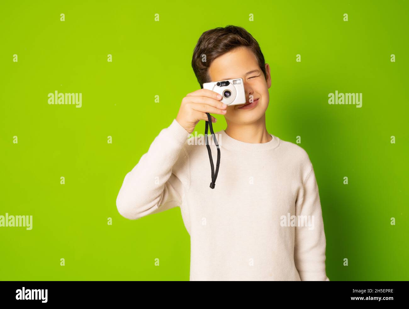 Little boy with photo camera isolated over green background Stock Photo ...