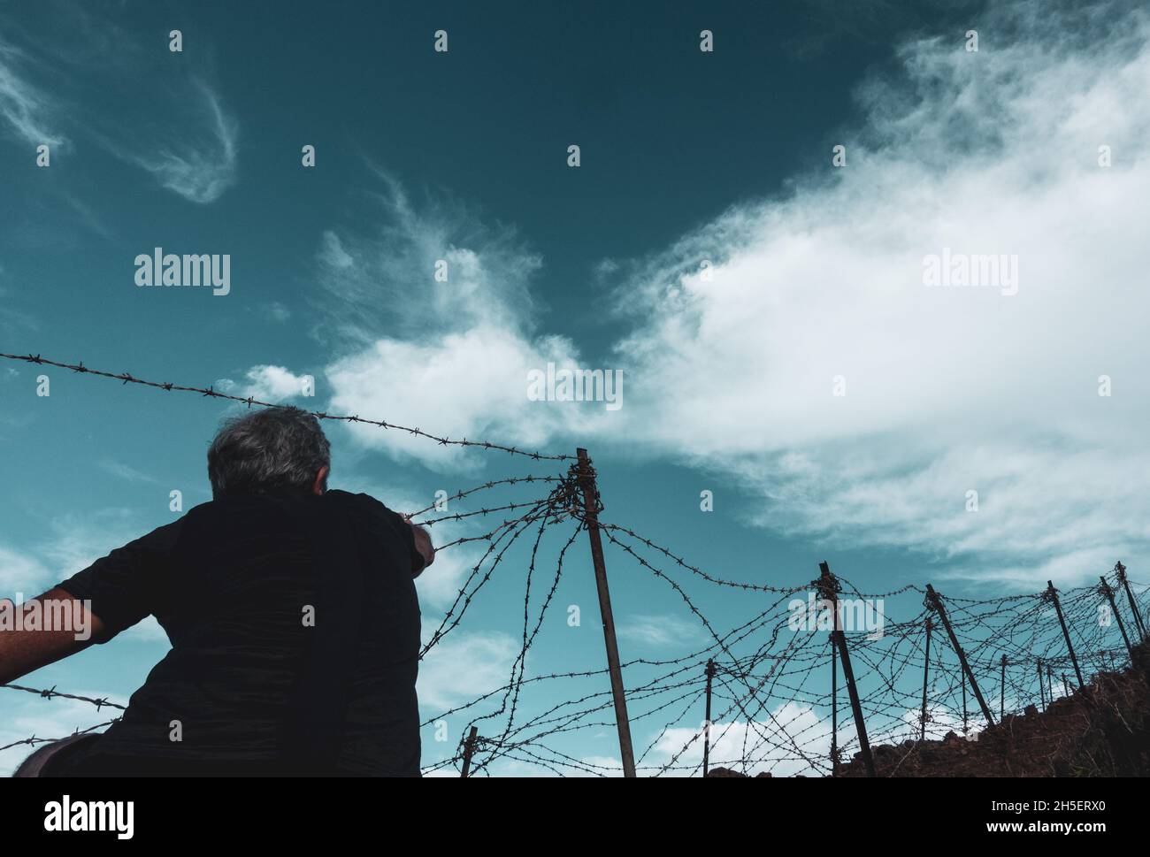 Man looking through barbed wire fence hi-res stock photography and ...