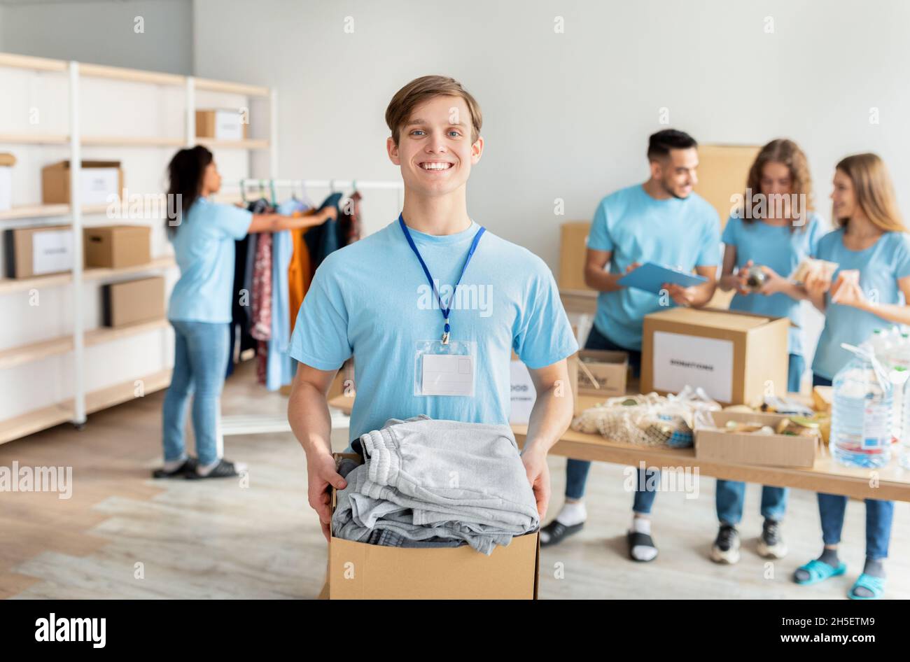 Portrait of male volunteer in uniform holding cardboard box with ...
