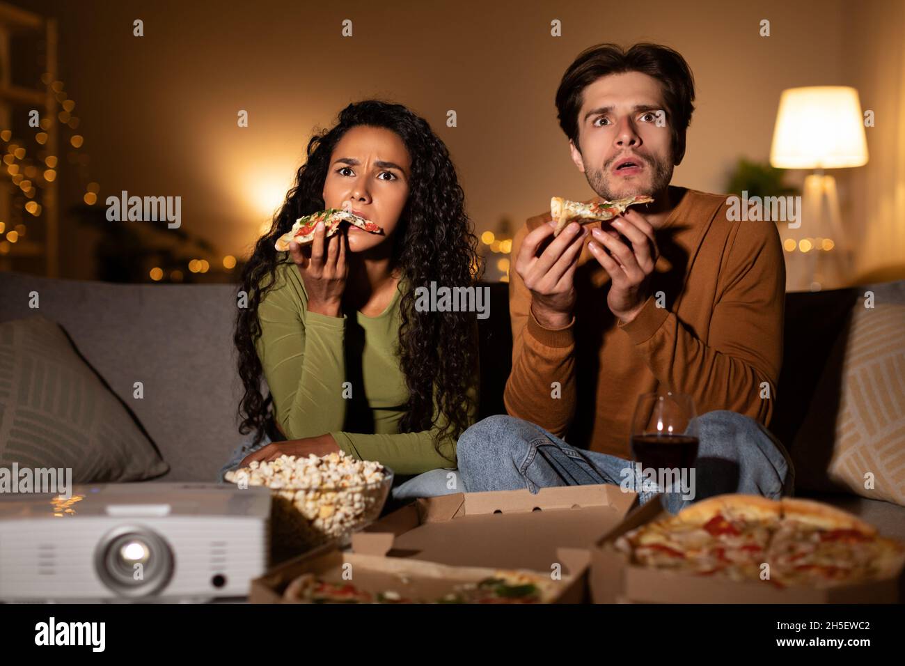Shocked Spouses Watching Horror Film Eating Pizza At Home Stock Photo ...