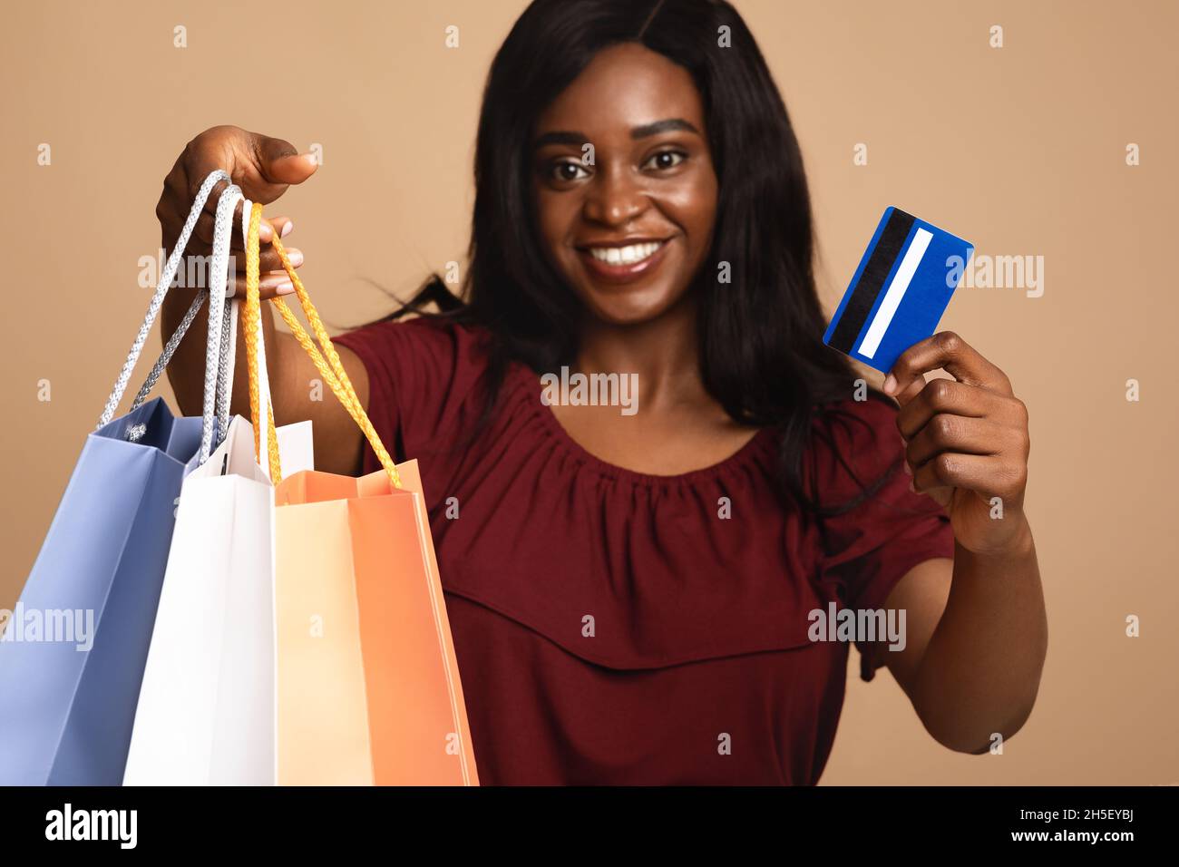 Cheerful african american woman shopaholic holding purchases and credit ...