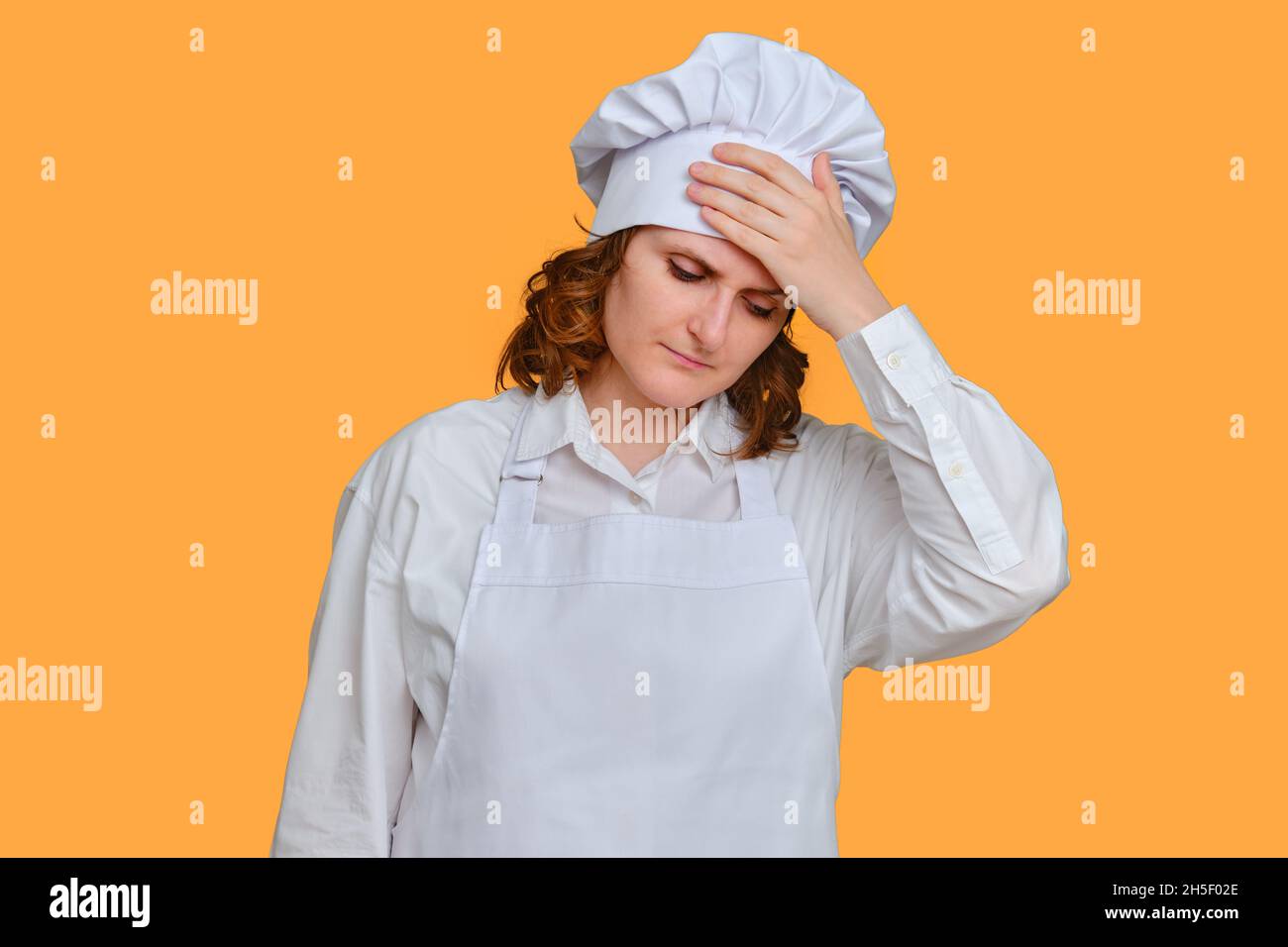 Sick woman chef is sad with her hands to her sore head on studio ...
