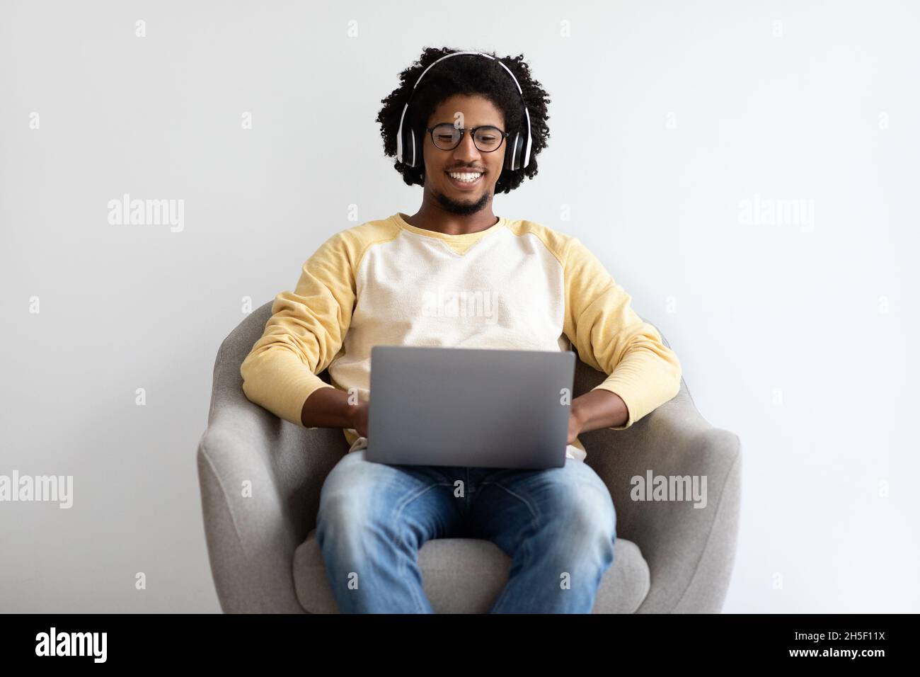 Smiling Young Black Guy Wearing Wireless Headphones Using Laptop ...