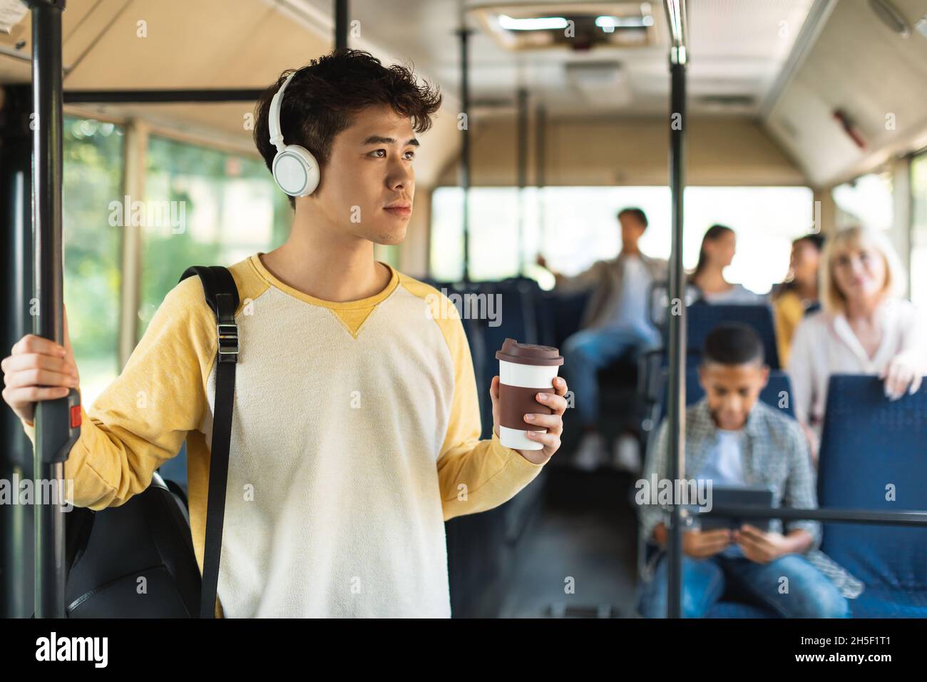 Focused asian guy listening music in bus drinking coffee Stock Photo ...