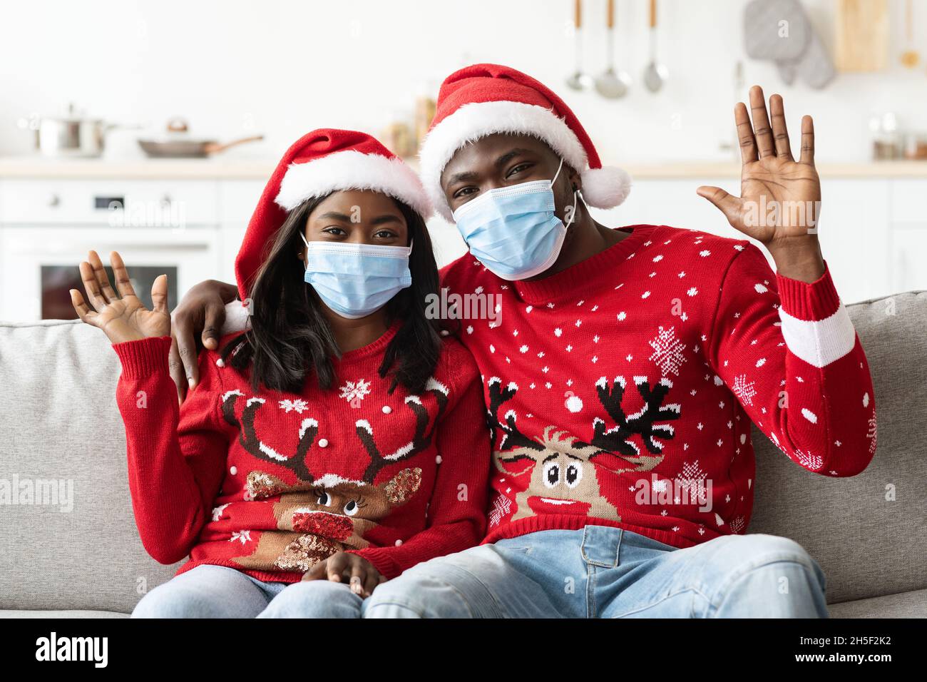 Couple in Santa hats and face masks waving at camera Stock Photo - Alamy