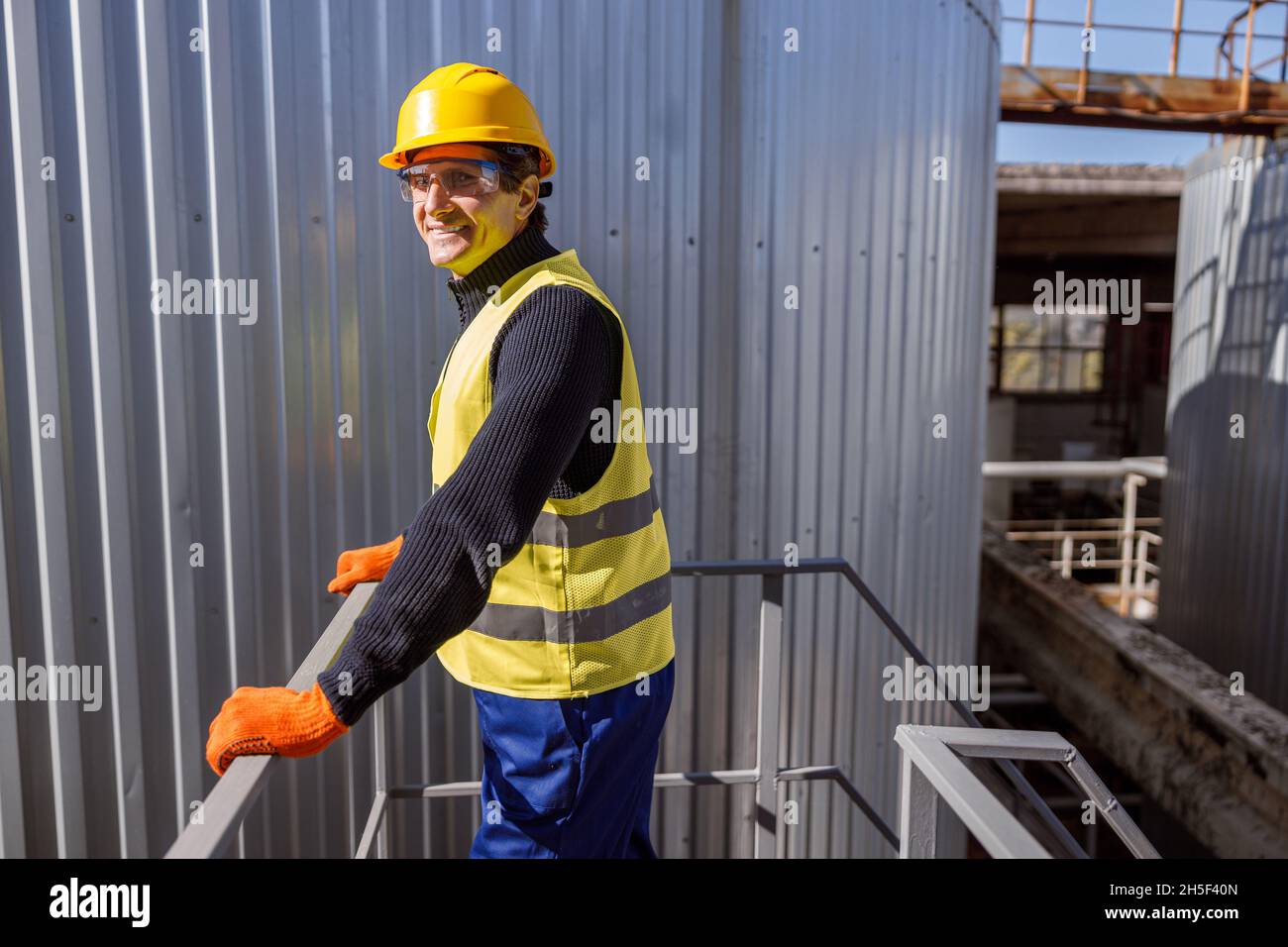 Joyful male engineer standing near metal storage container outdoors ...