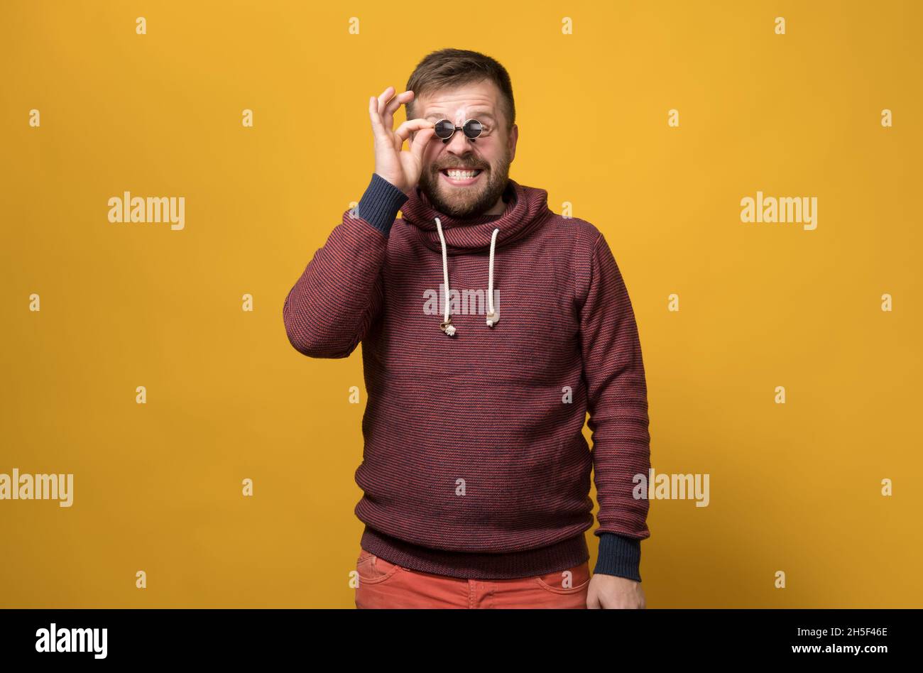 Cheerful Caucasian bearded man holds toy sunglasses like pince-nez to ...