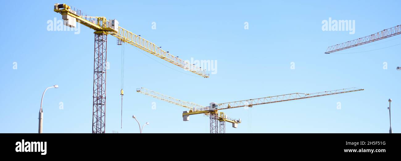 Many construction cranes standing near multi-storey buildings at site ...