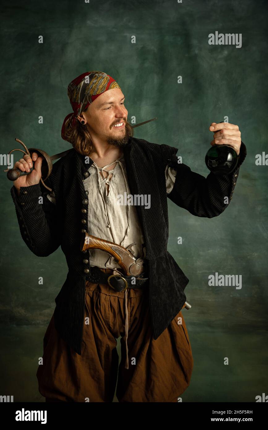 Portrait of one smiling man, medeival pirate holding bottle of rum ...