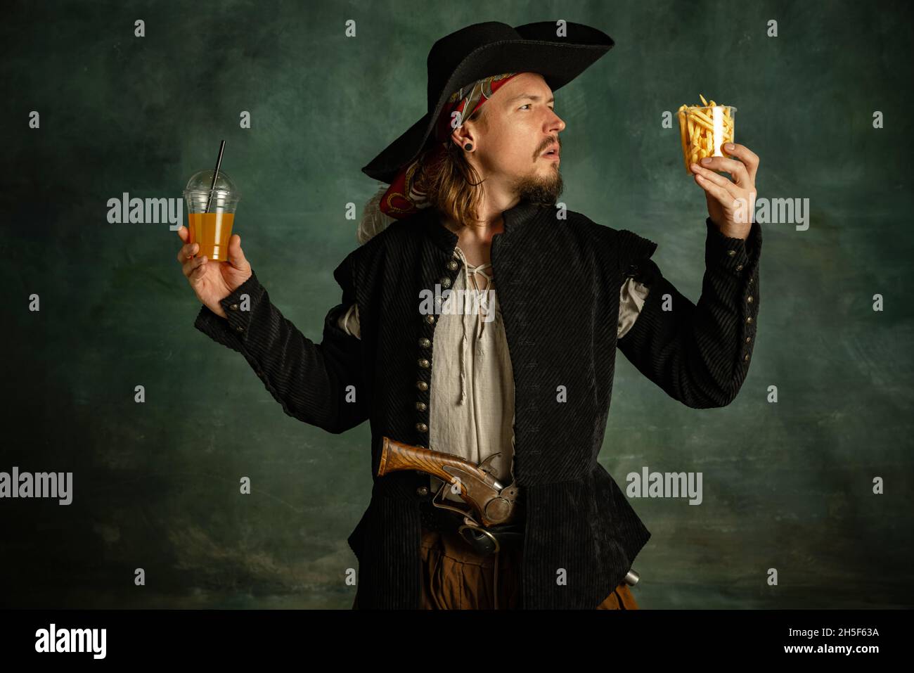 Portrait of one brutal man, medeival pirate holding orange juice and ...