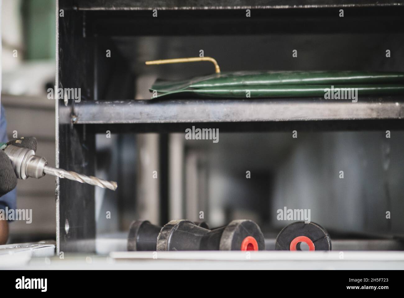 Worker with a drill drills a hole in the iron structure Stock Photo - Alamy