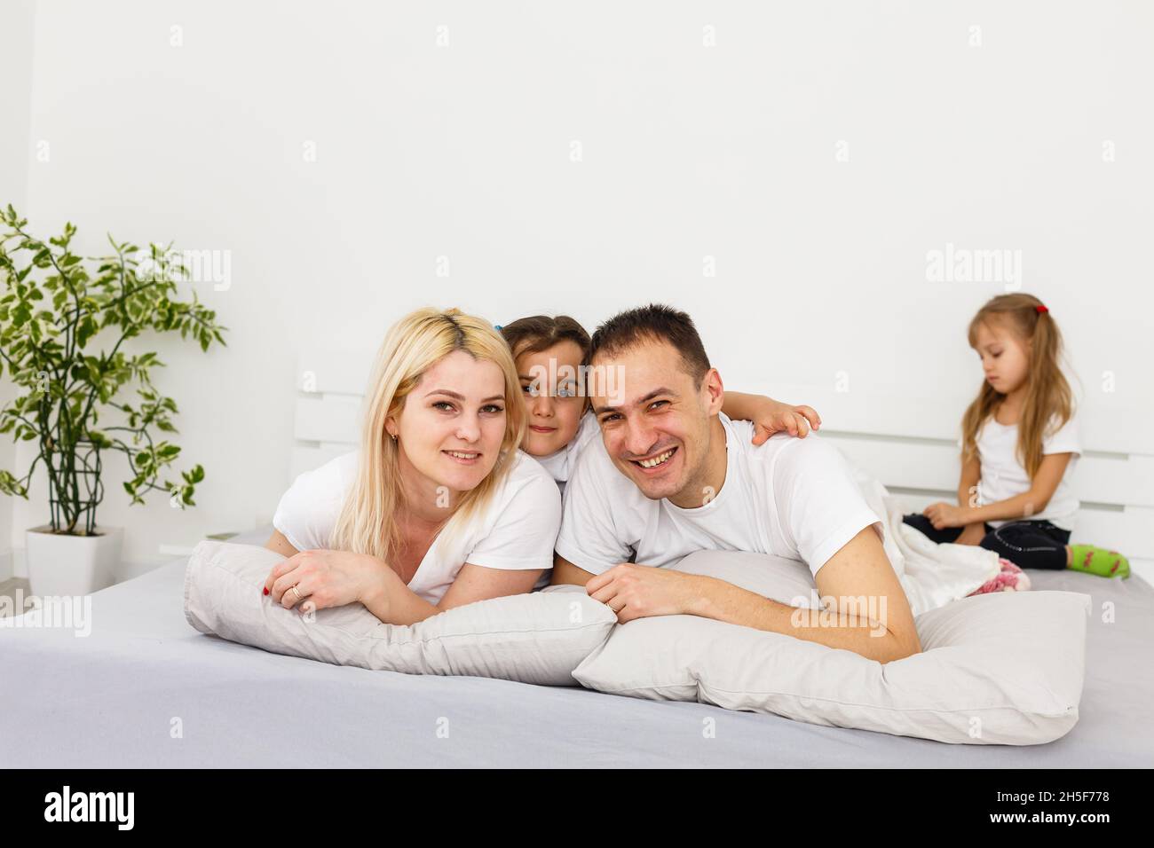 Young family resting together in parent's bed Stock Photo - Alamy