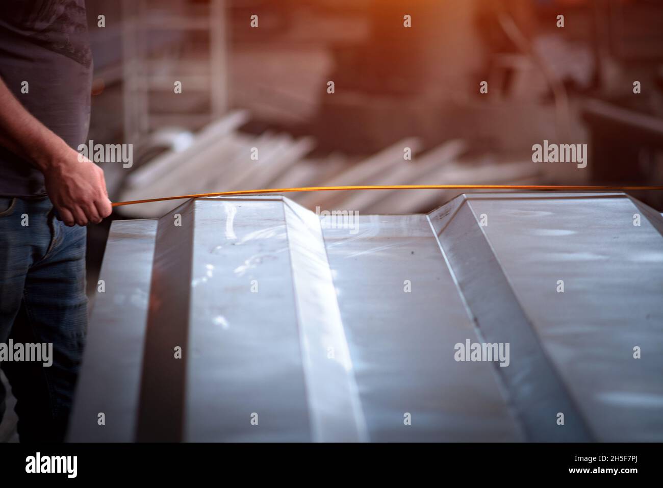 The worker measures the length of the iron sheet with a measuring tape ...