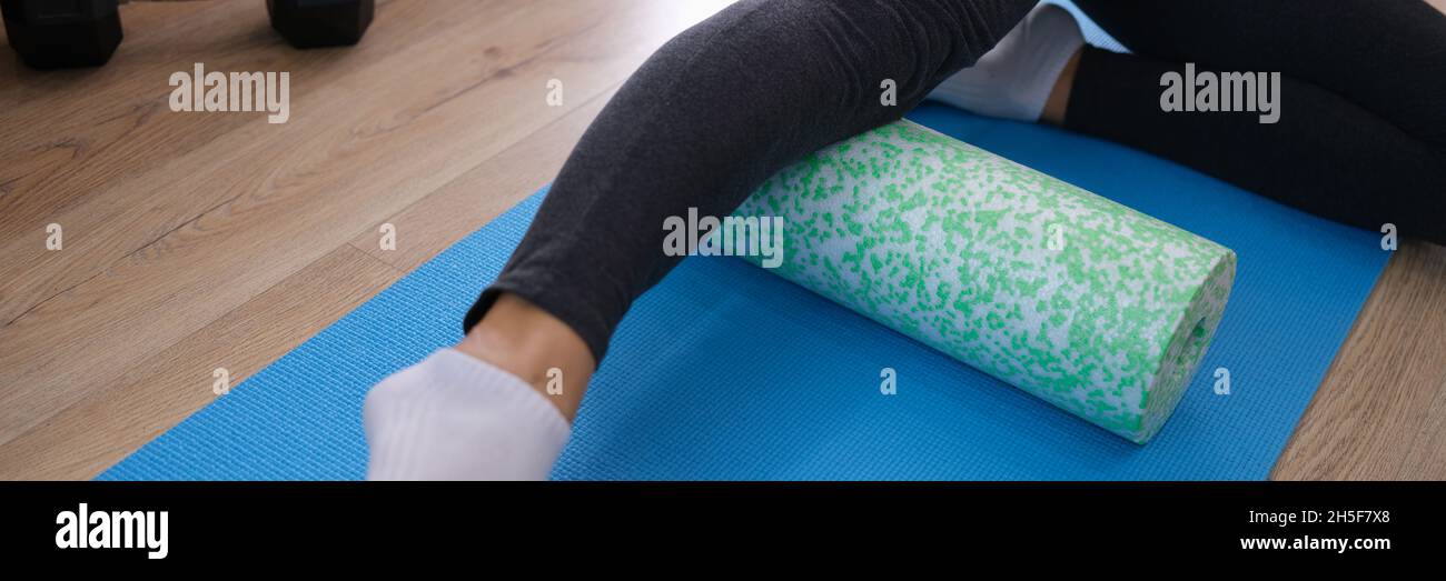 Fitness woman in sportswear lying on yoga mat exercising with foam ...