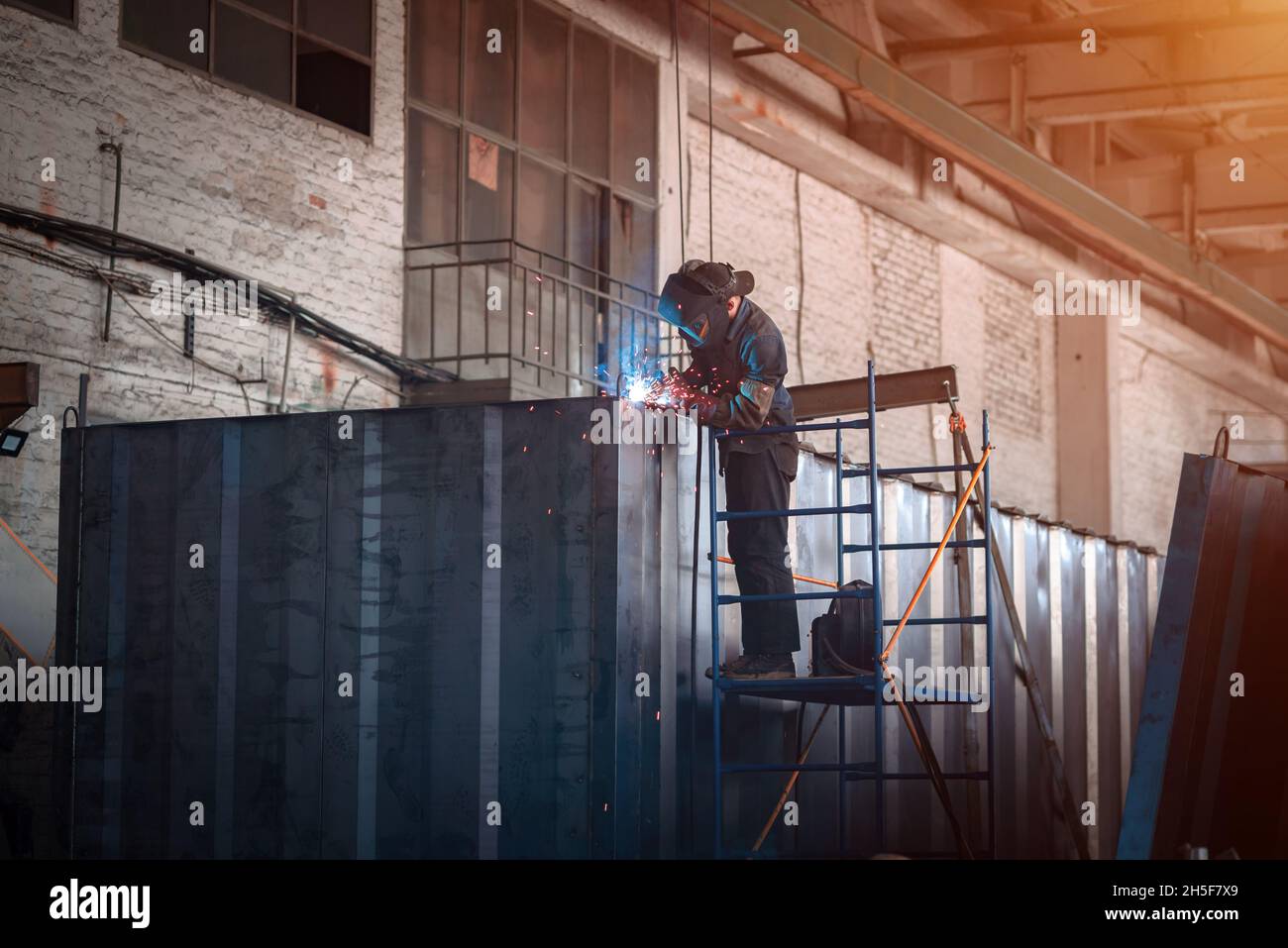 Worker at the factory to weld the iron container Stock Photo - Alamy