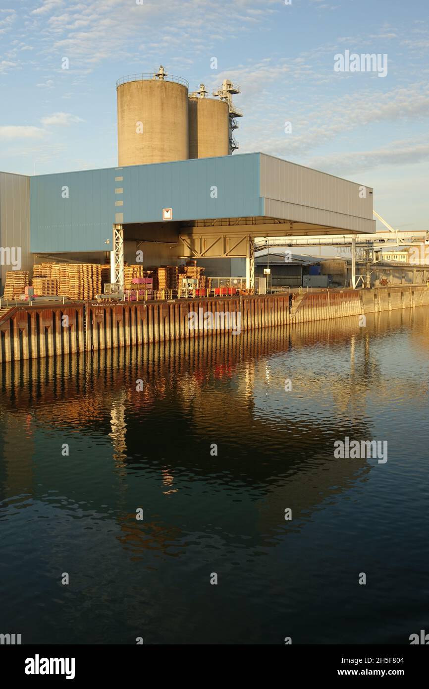 Cargo halls and harbour buildings reflecting in the water at dusk ...