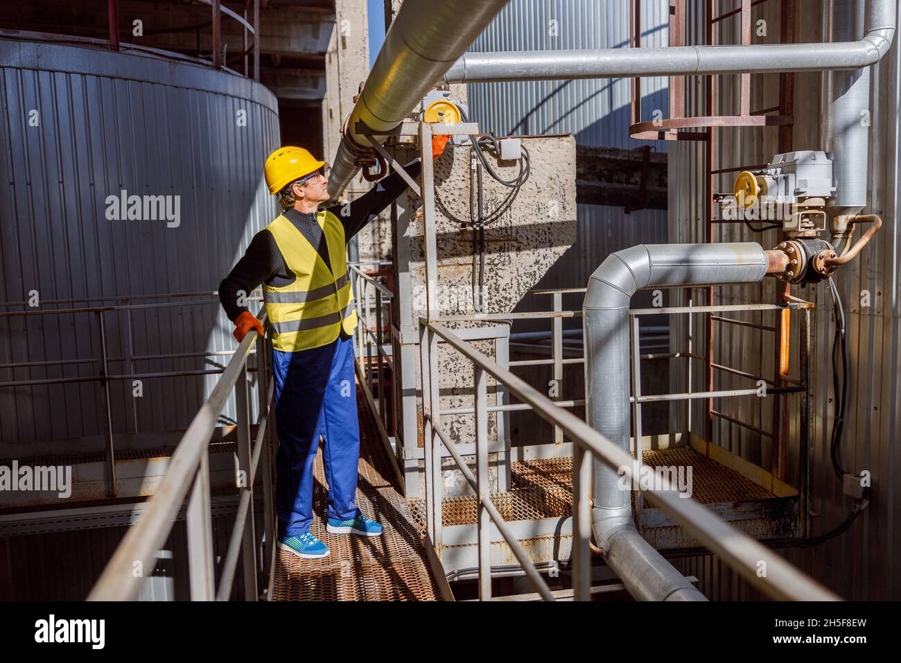 Male engineer checking metal pipe at factory Stock Photo - Alamy