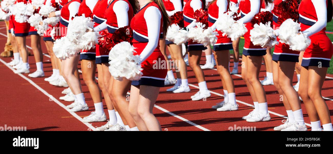 High school cheerleaders wearing red and white uniforms cheering on the ...