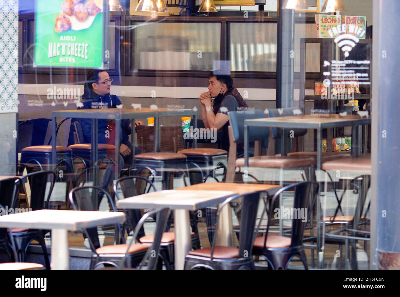 Empty seats are seen outside a restaurant where people are seen inside ...