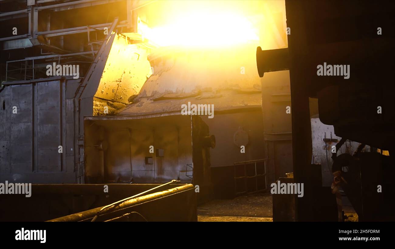 Interior view of steel mill with huge ladle of burning metal alloy ...