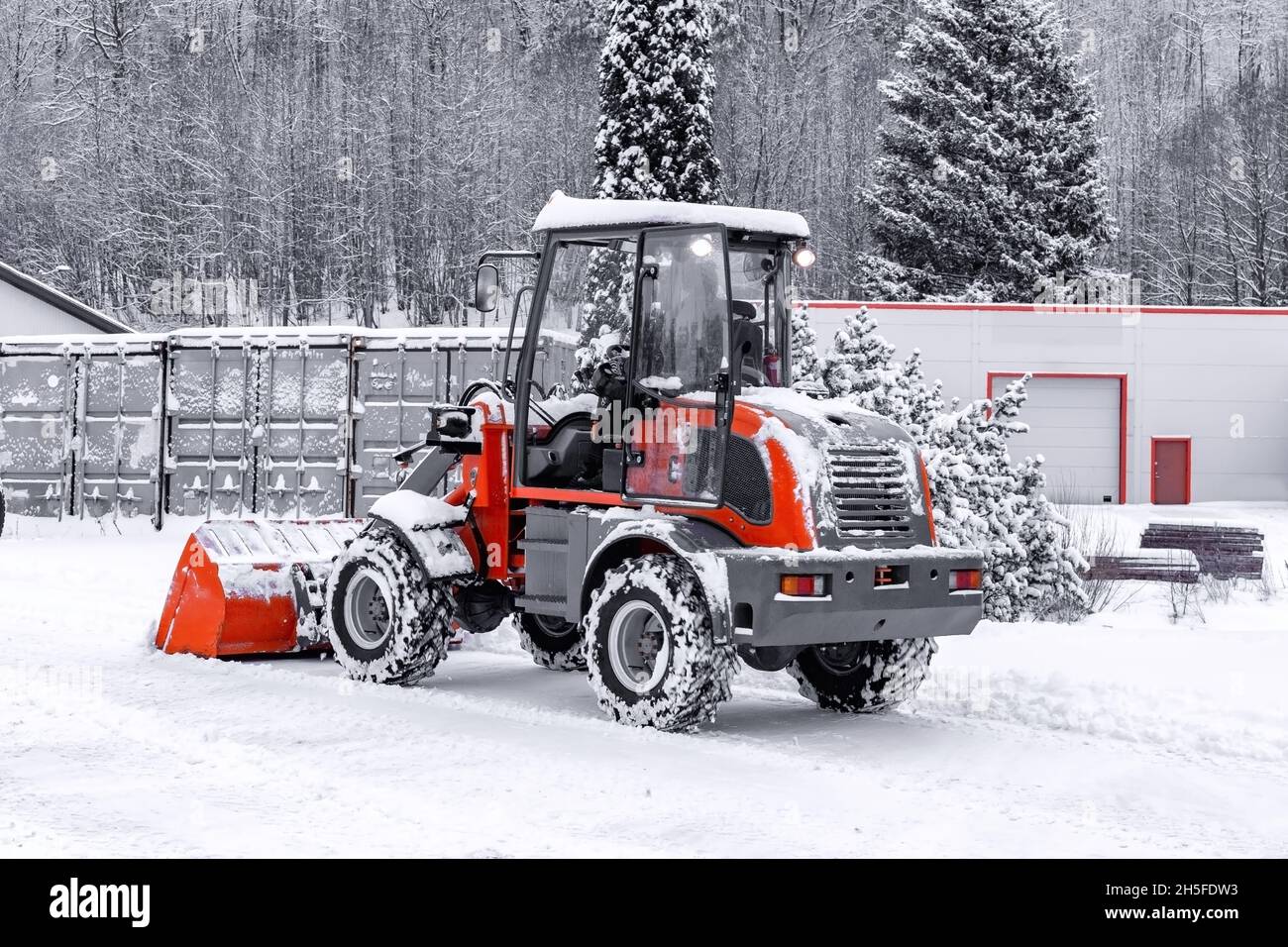 Man on red tractor with snowplow removing snow during the snowfall ...