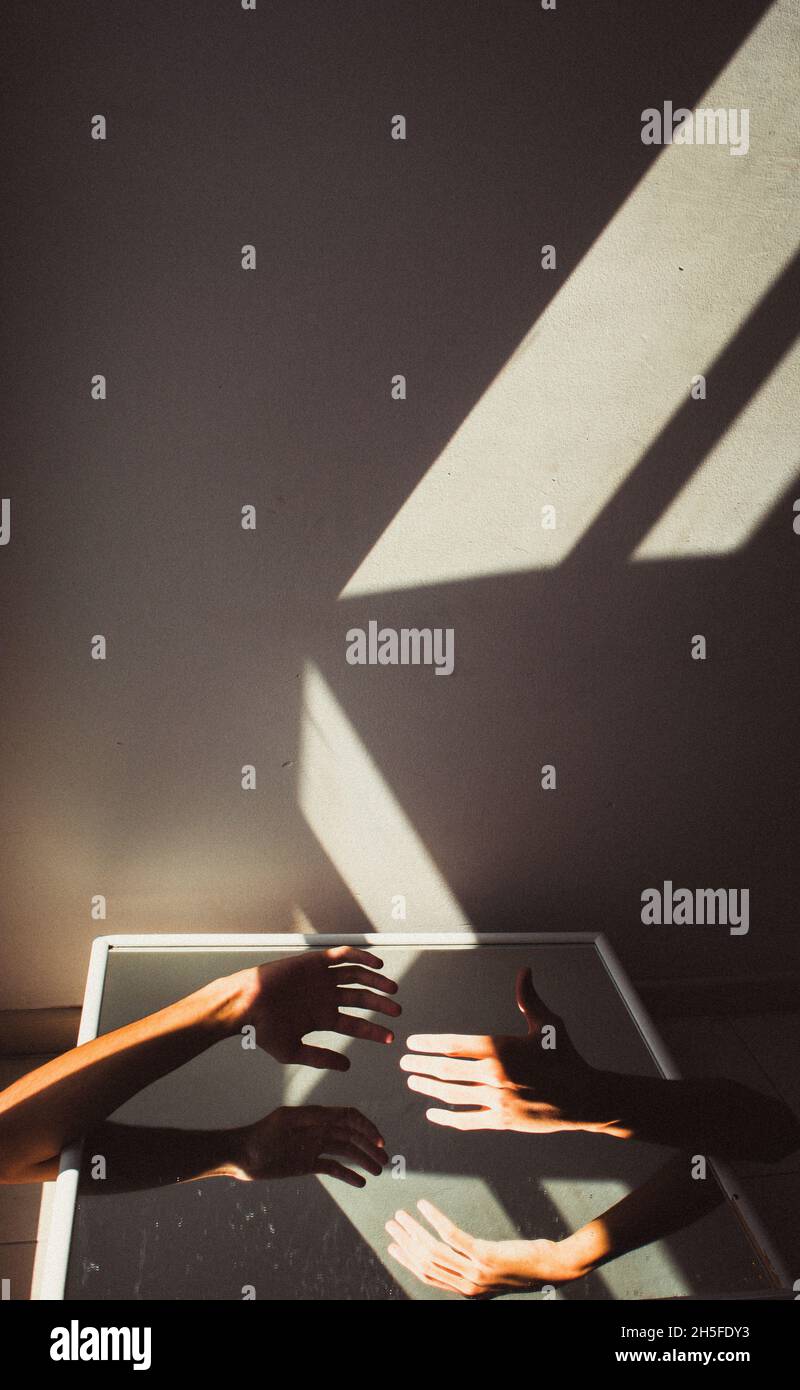 Vertical shot of the hands of two people reaching for each other under ...