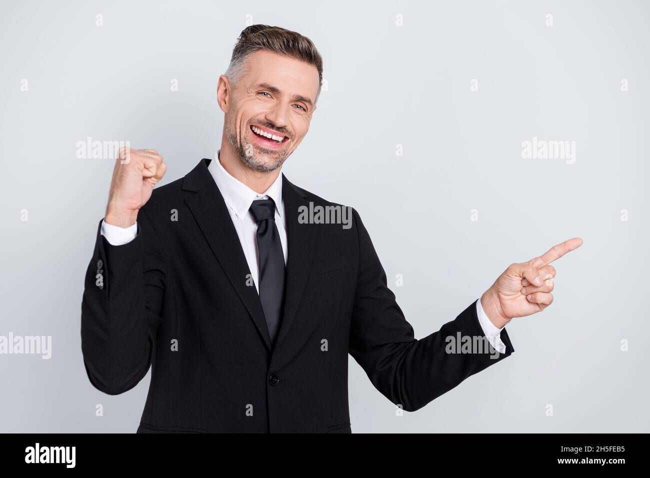 Photo of positive lucky young manager wear black jacket rising fist ...