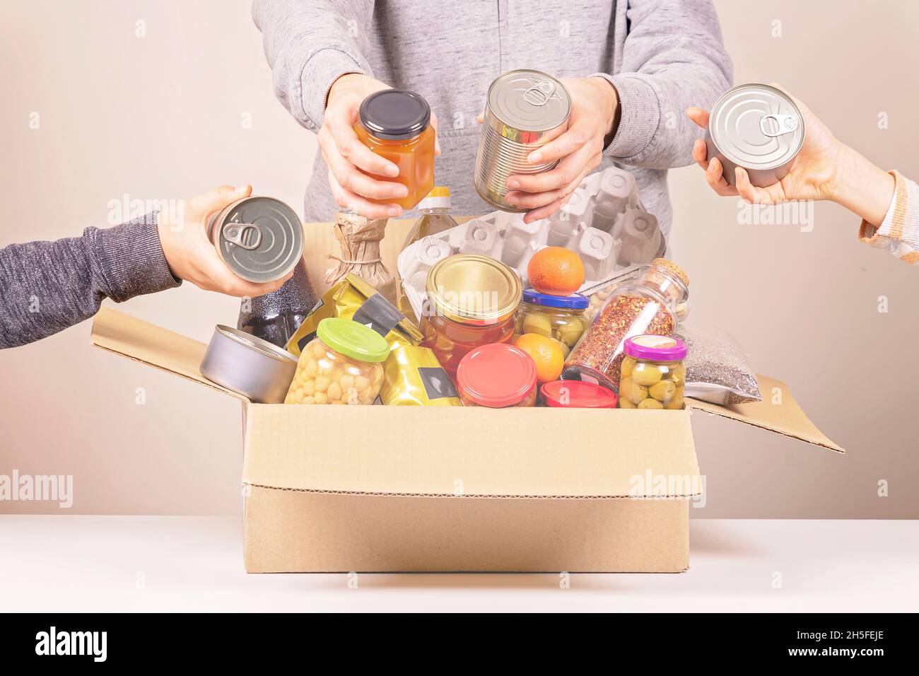 Volunteers hands collecting grocery products to food donations box for ...