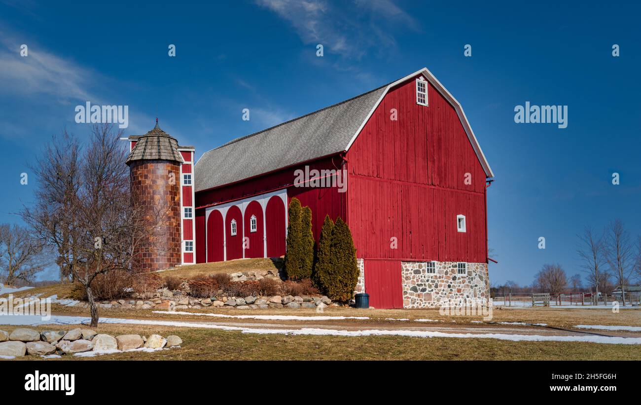 Small red wooden barn in a field under the sunlight and a blue sky in ...