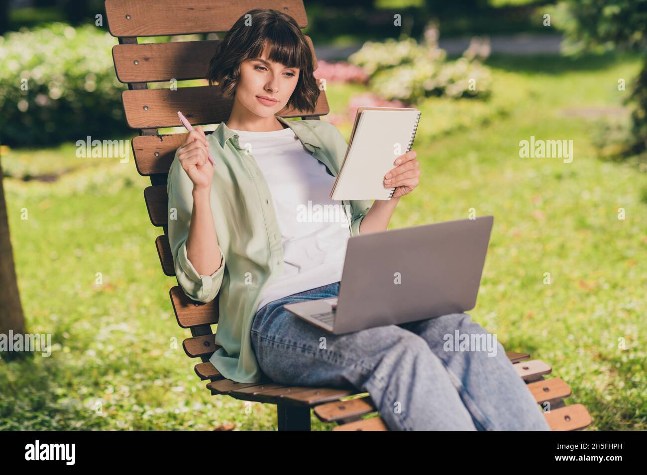Portrait photo smiling young girl sitting on bench working on computer ...