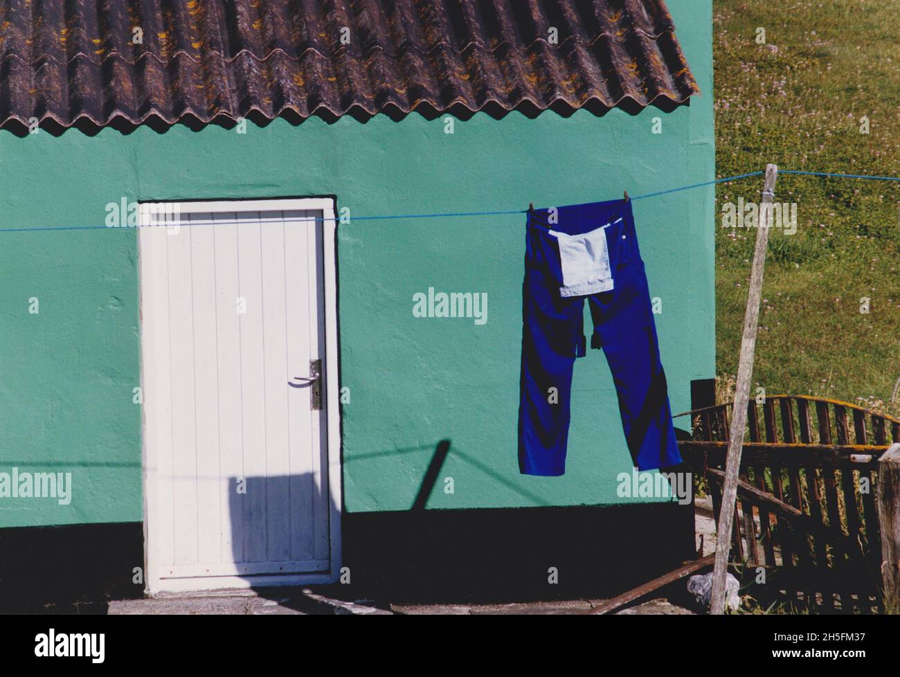 Blue working trousers on a washing line in front of a green building ...