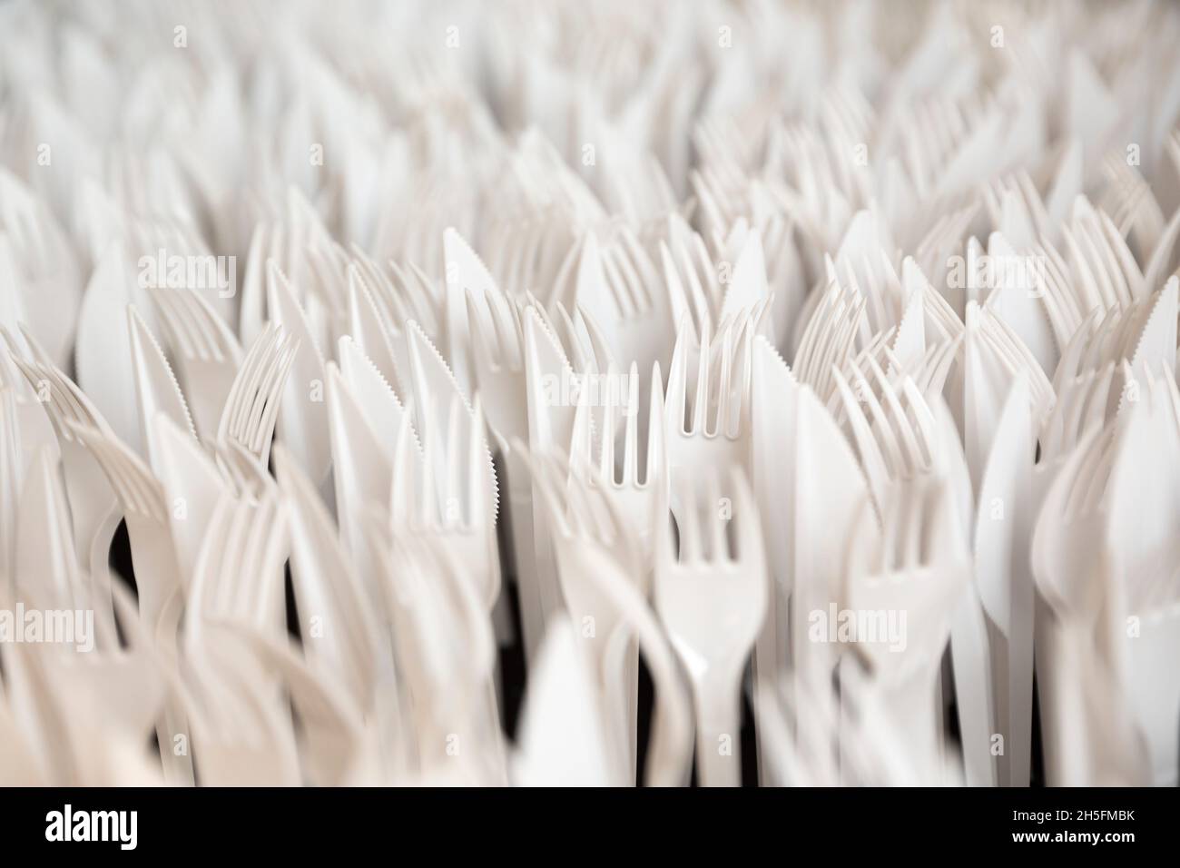 White plastic forks and knifes are seen stacked. Most disposable ...