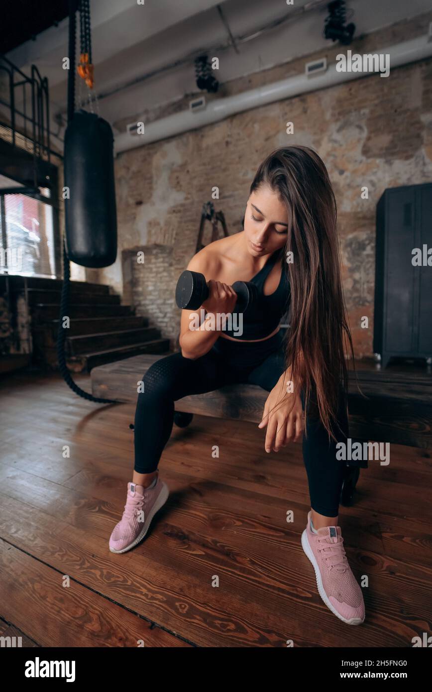 Young woman pumps up the muscles by one arm lifting dumbbell Stock ...