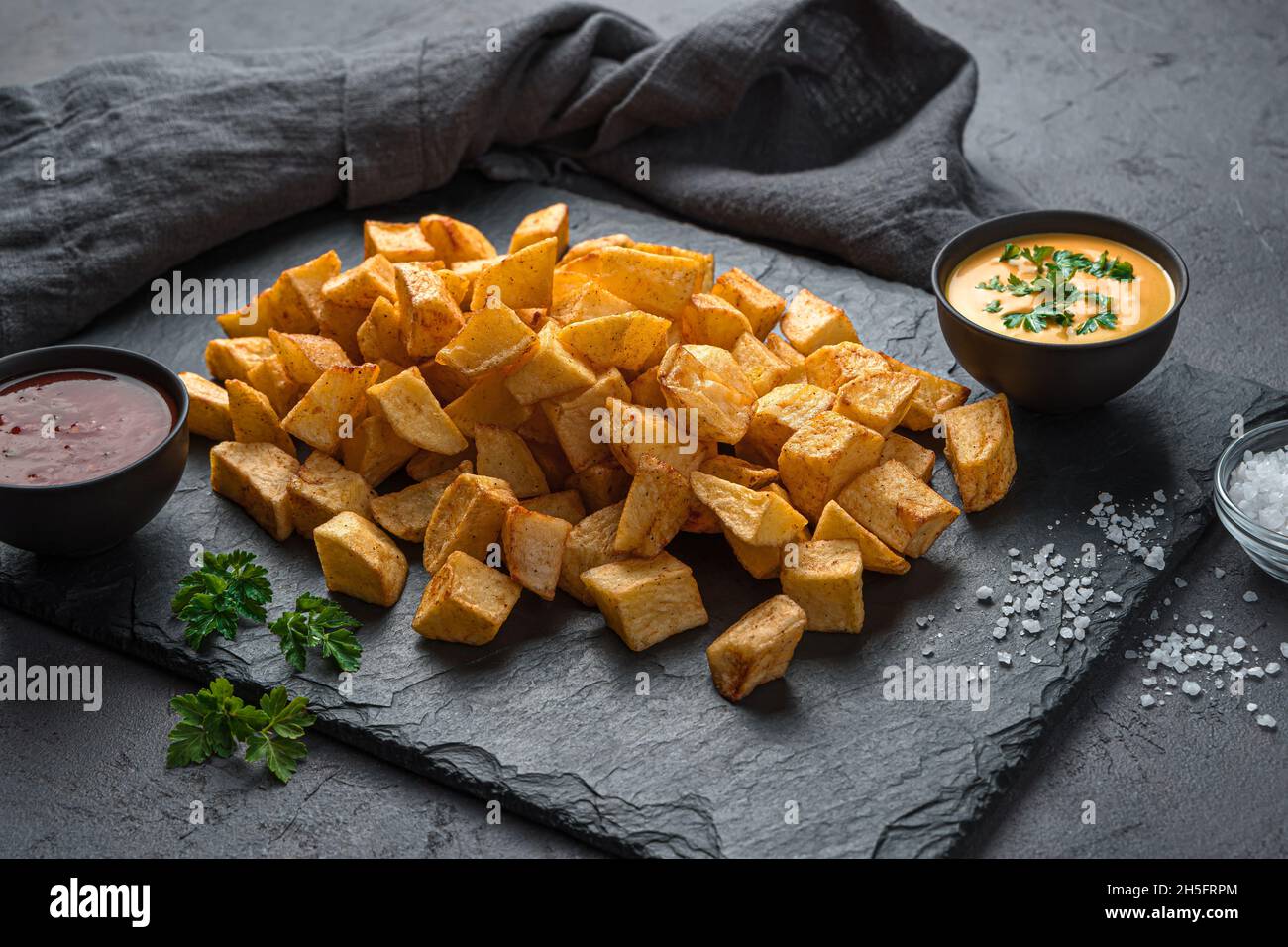 Fried potatoes with spices and sauces, patatas bravas on a black ...