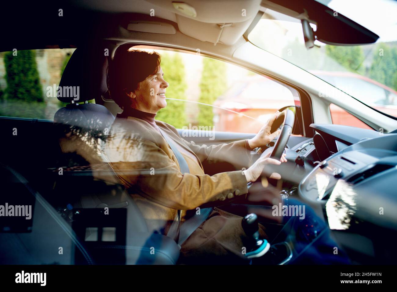 Middle aged woman driving home a car smiling Stock Photo - Alamy