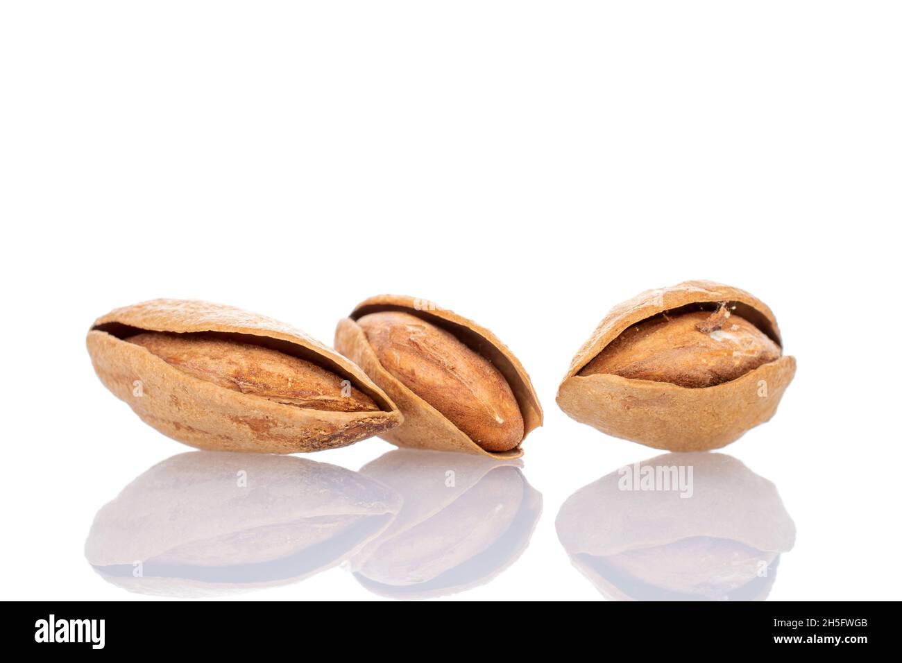 Three nuts of unpeeled dried almonds, close-up, isolated on white Stock ...