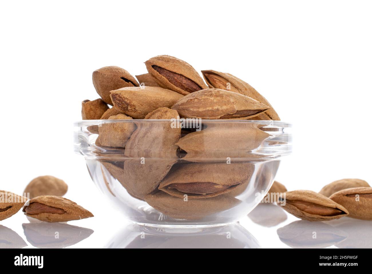 Dried unpeeled almonds in a glass bowl, close-up, isolated on white ...