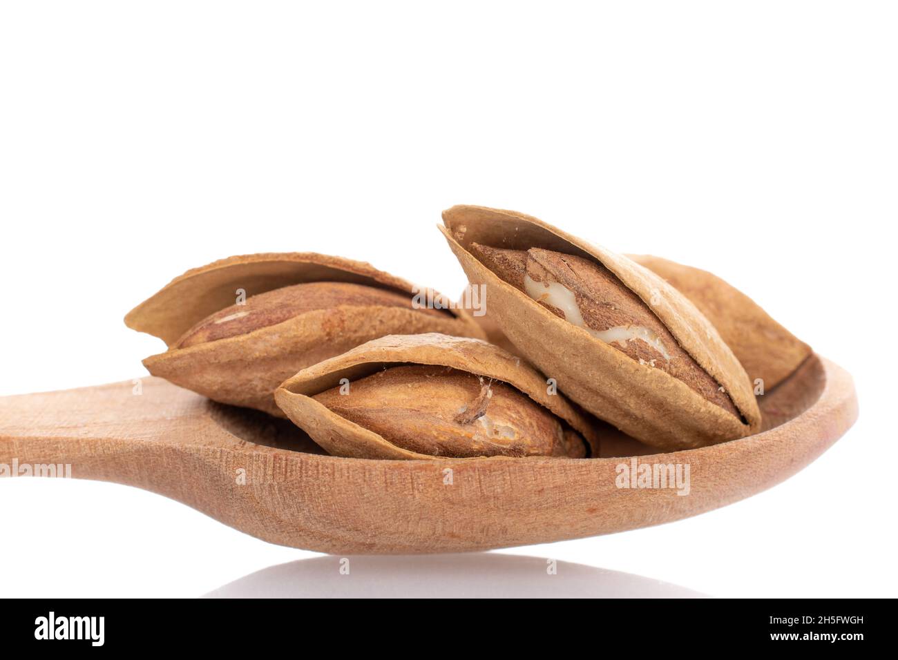 Dried unpeeled almonds with a wooden spoon, close-up, isolated on white ...