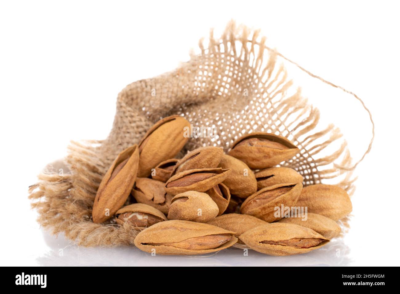 Dried unpeeled almonds with a jute bag, close-up, isolated on white ...