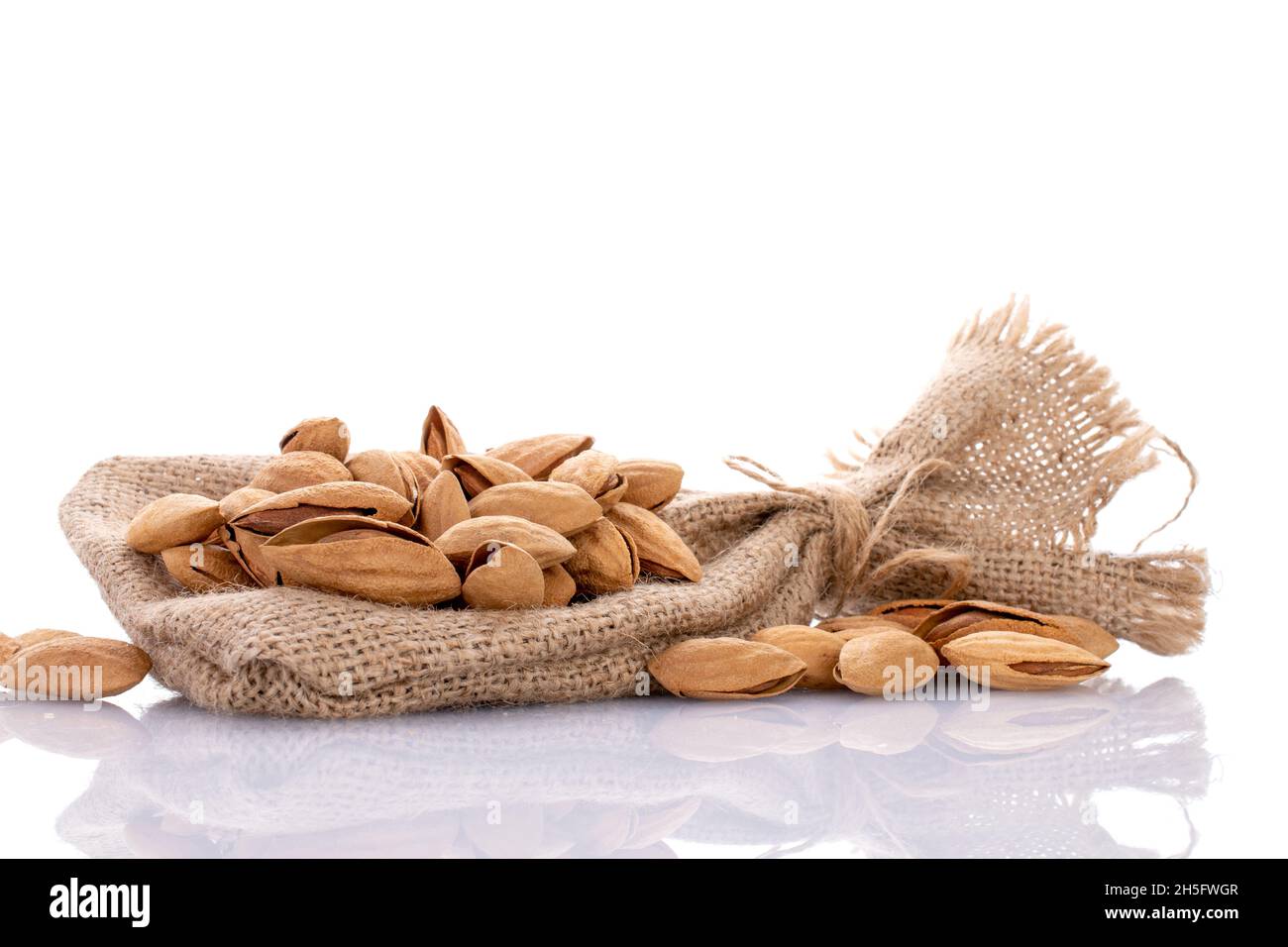 Dried unpeeled almonds with a jute bag, close-up, isolated on white ...