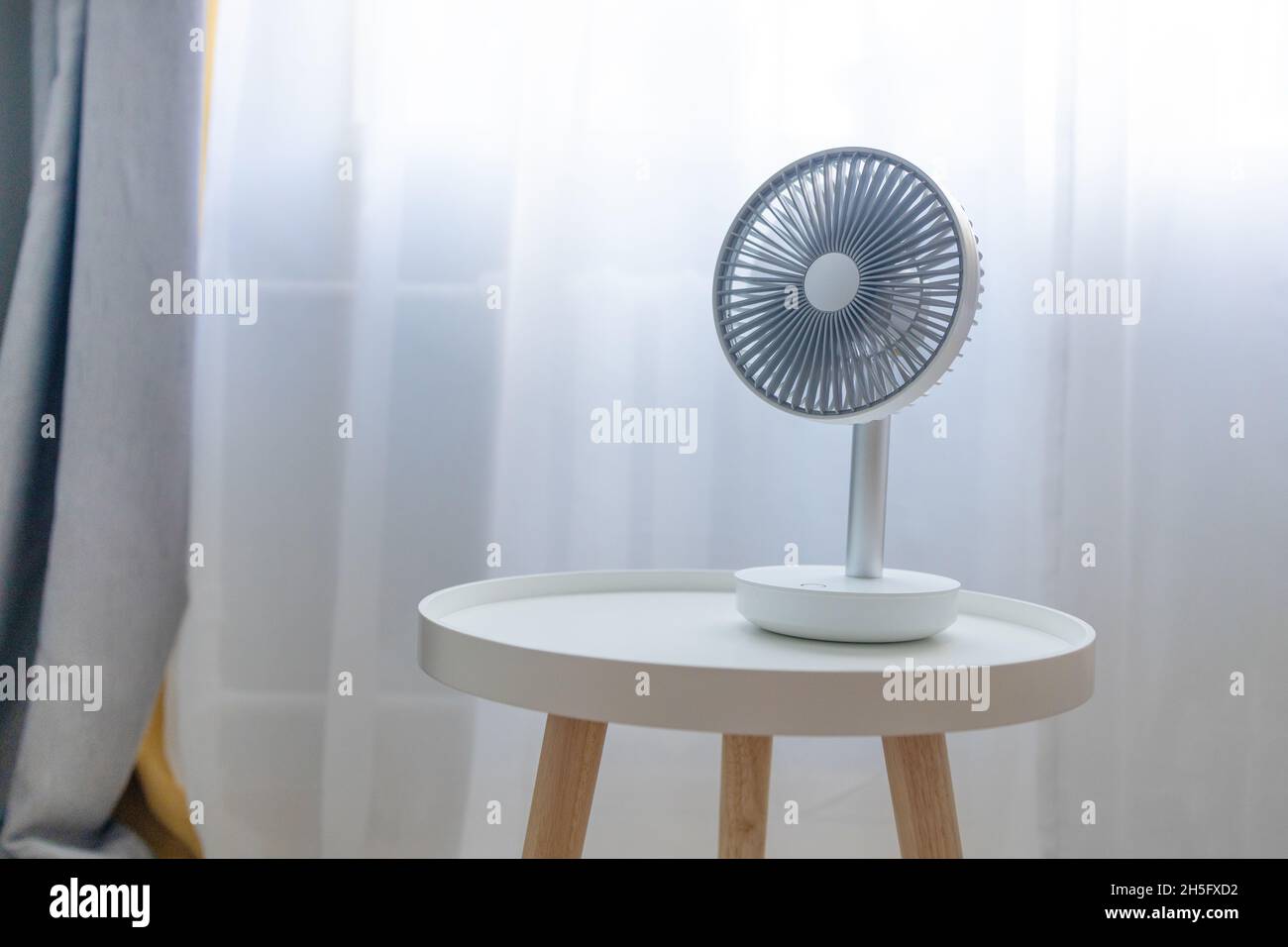 Modern electric portable fan on a white coffee table. Cooling of high ...