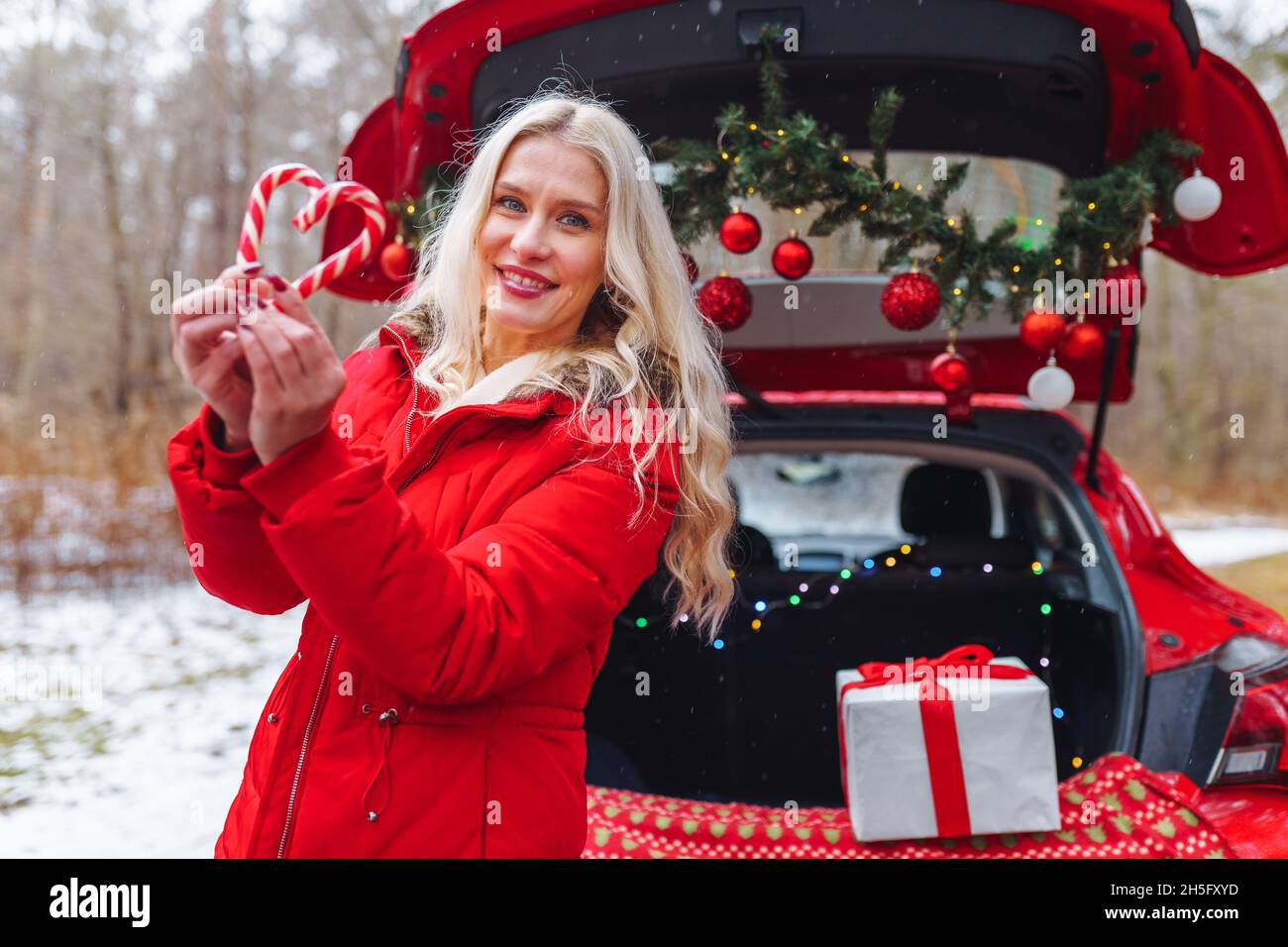 Smiling blonde woman in red jacket with heart-shaped red and white ...