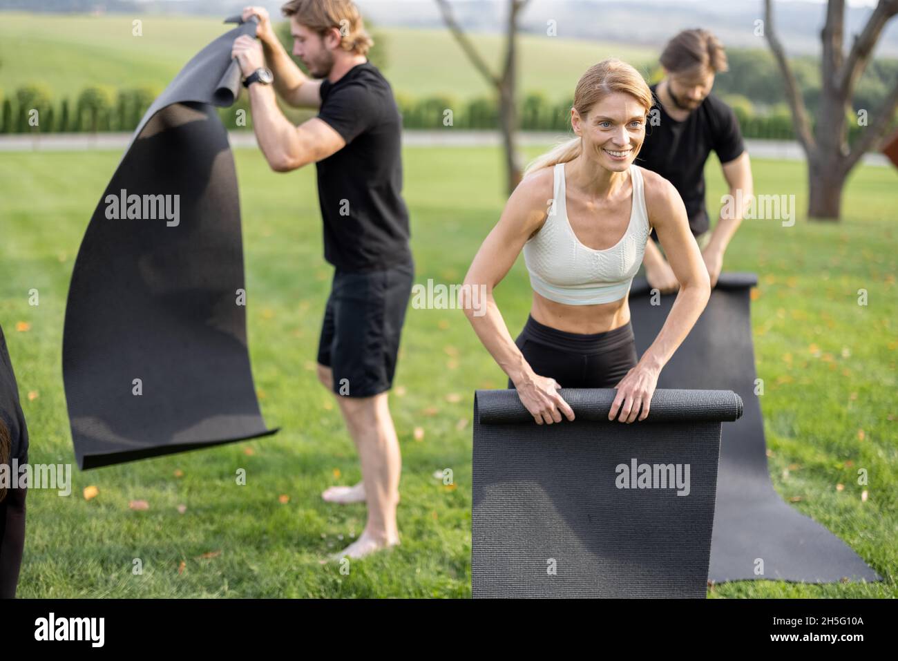 People fold fitness mats after training on meadow Stock Photo - Alamy