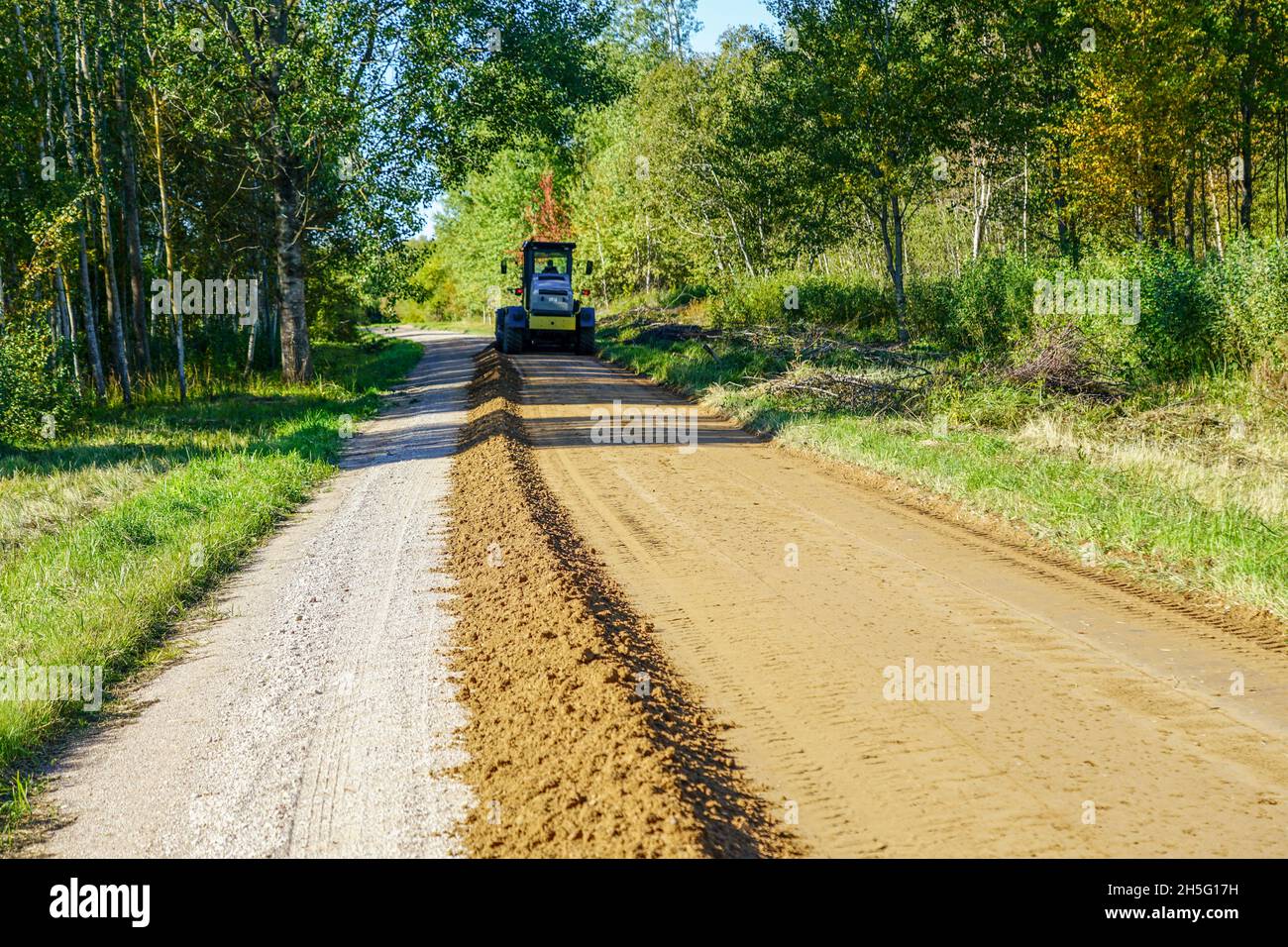 The grader is working on leveling gravel on a gravel road in a rural ...