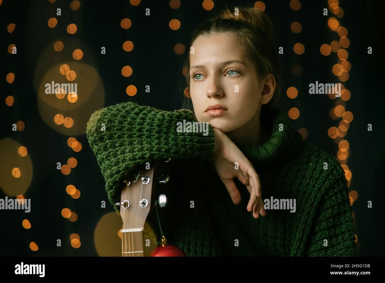 A beautiful teenager girl dreamily looks to the side, leaning on the ...