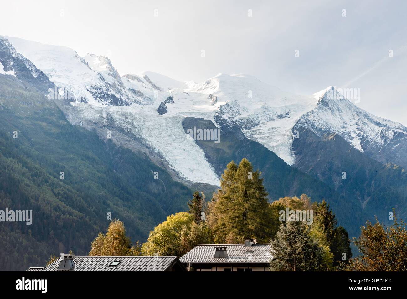 Rooftops and pine trees with snow-capped mountains in background, the ...