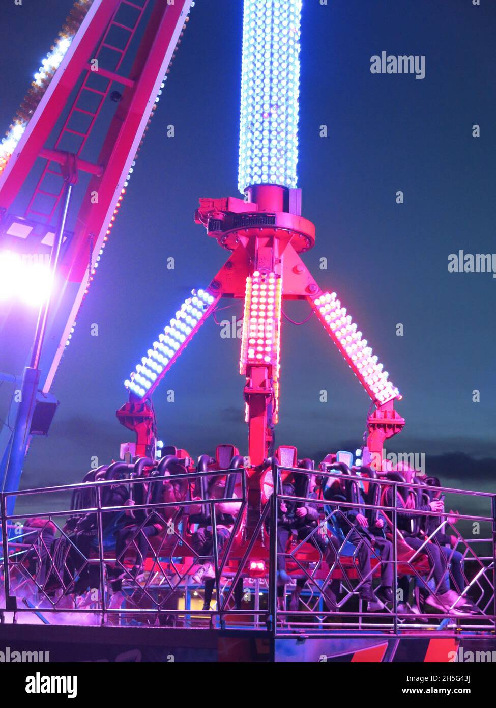 The illuminated hydraulic arm and circular structure of a fairground ...