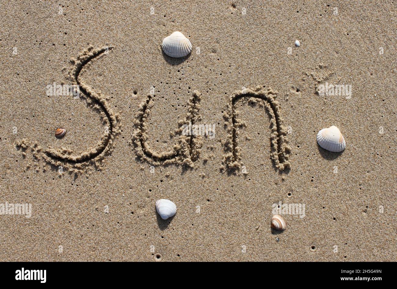 on the beach is carved with letters in the smooth sand the writing SUN ...